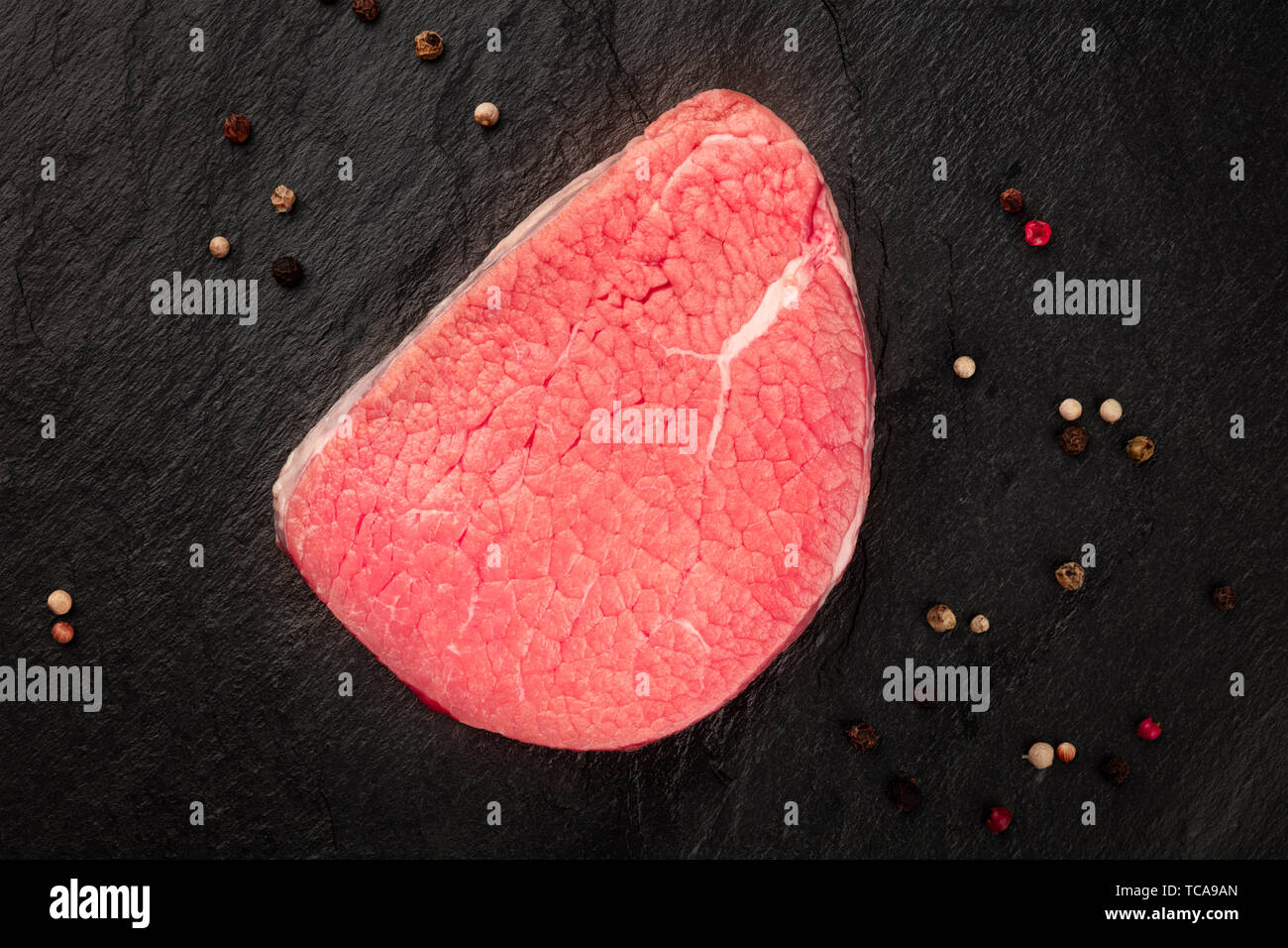 A photo of a steak of eye round beef, a raw cut, with pepper, shot from ...