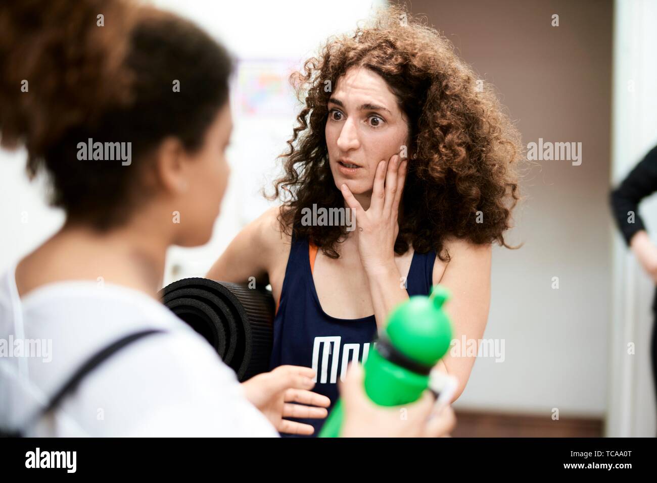 apprehensive woman listening to story of friend in fitness studio Stock ...