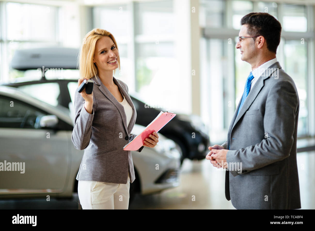 Professional salesperson during work with customer at car dealership ...