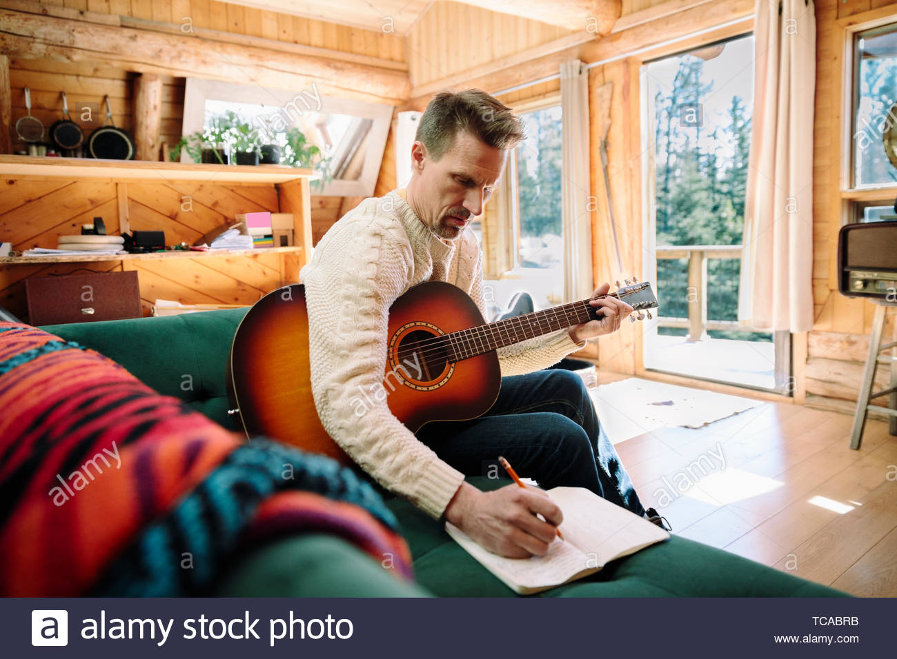 Man with guitar song writing in cabin Stock Photo - Alamy