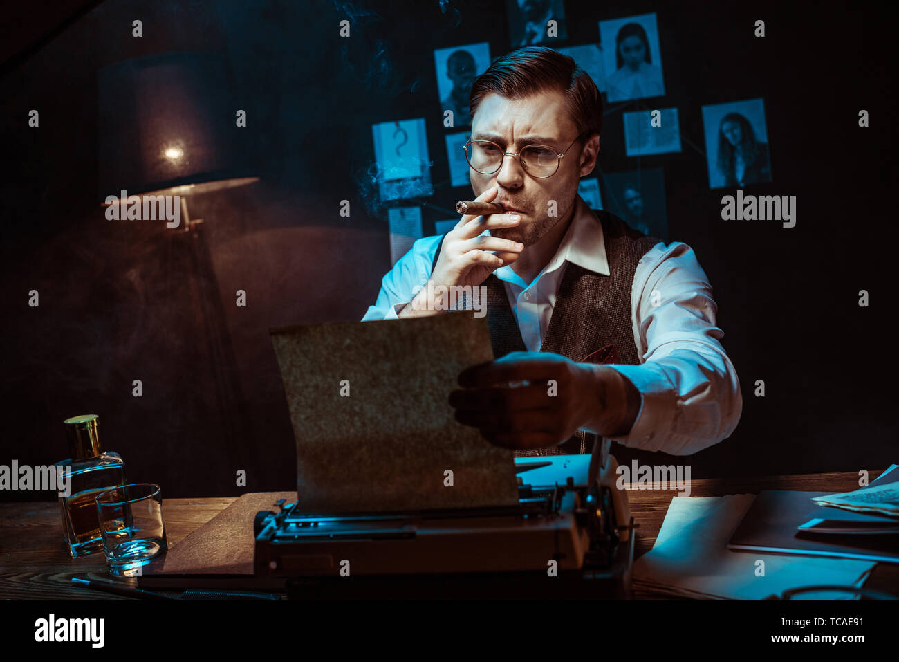 Detective in glasses smoking cigar while using typewriter in dark ...