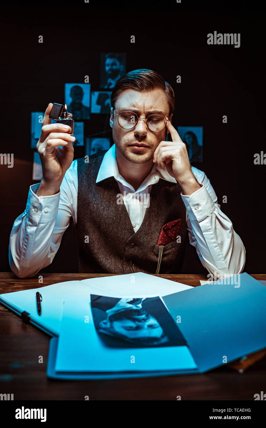 Pensive detective holding lighter with closed eyes in office Stock ...