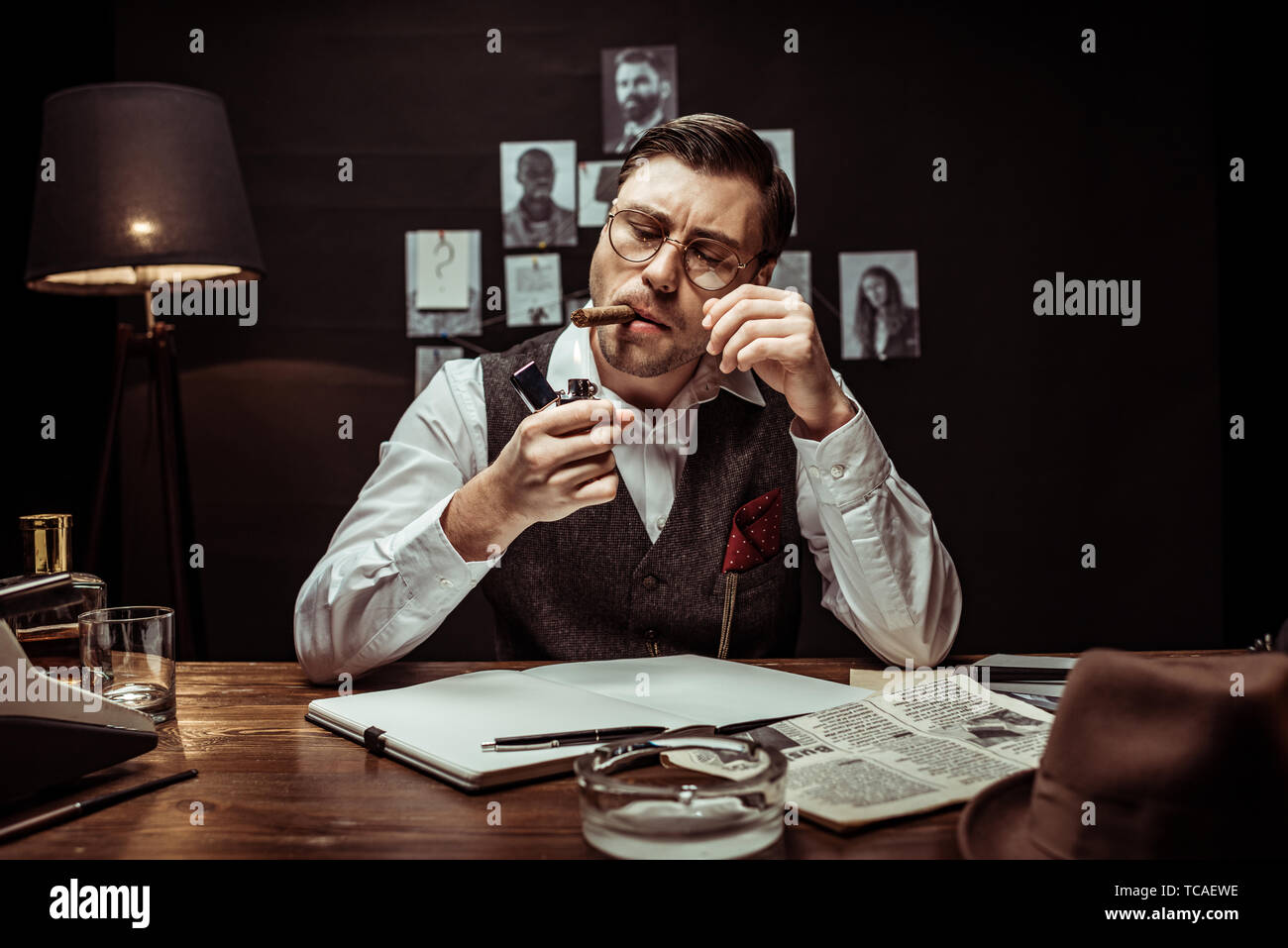 Detective in glasses and white shirt lighting cigar in dark office ...