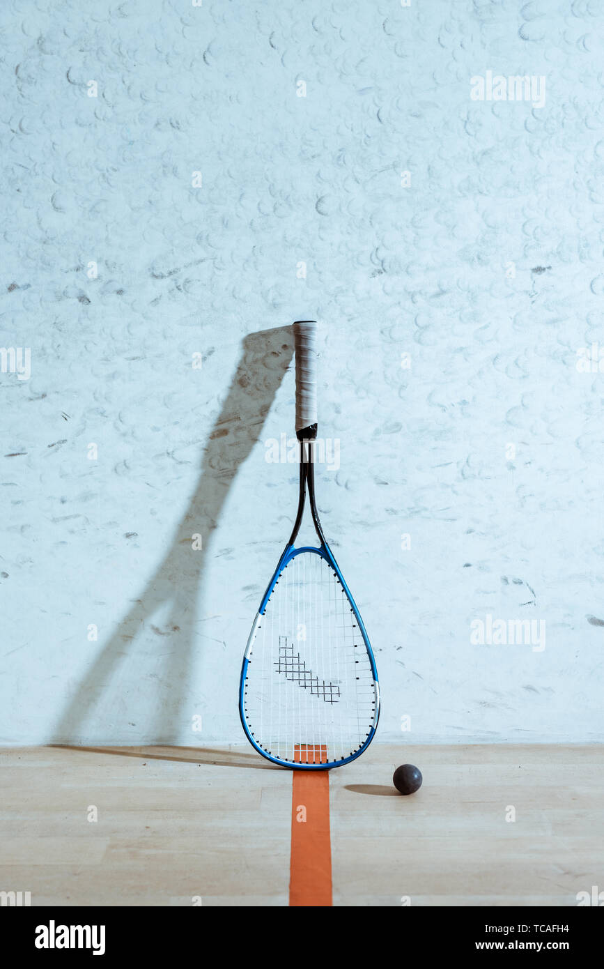 One squash racket and ball on wooden floor in four-walled court Stock ...