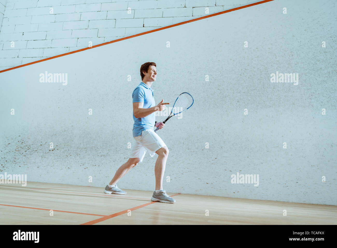 Full length view of smiling squash player pointing with finger Stock ...