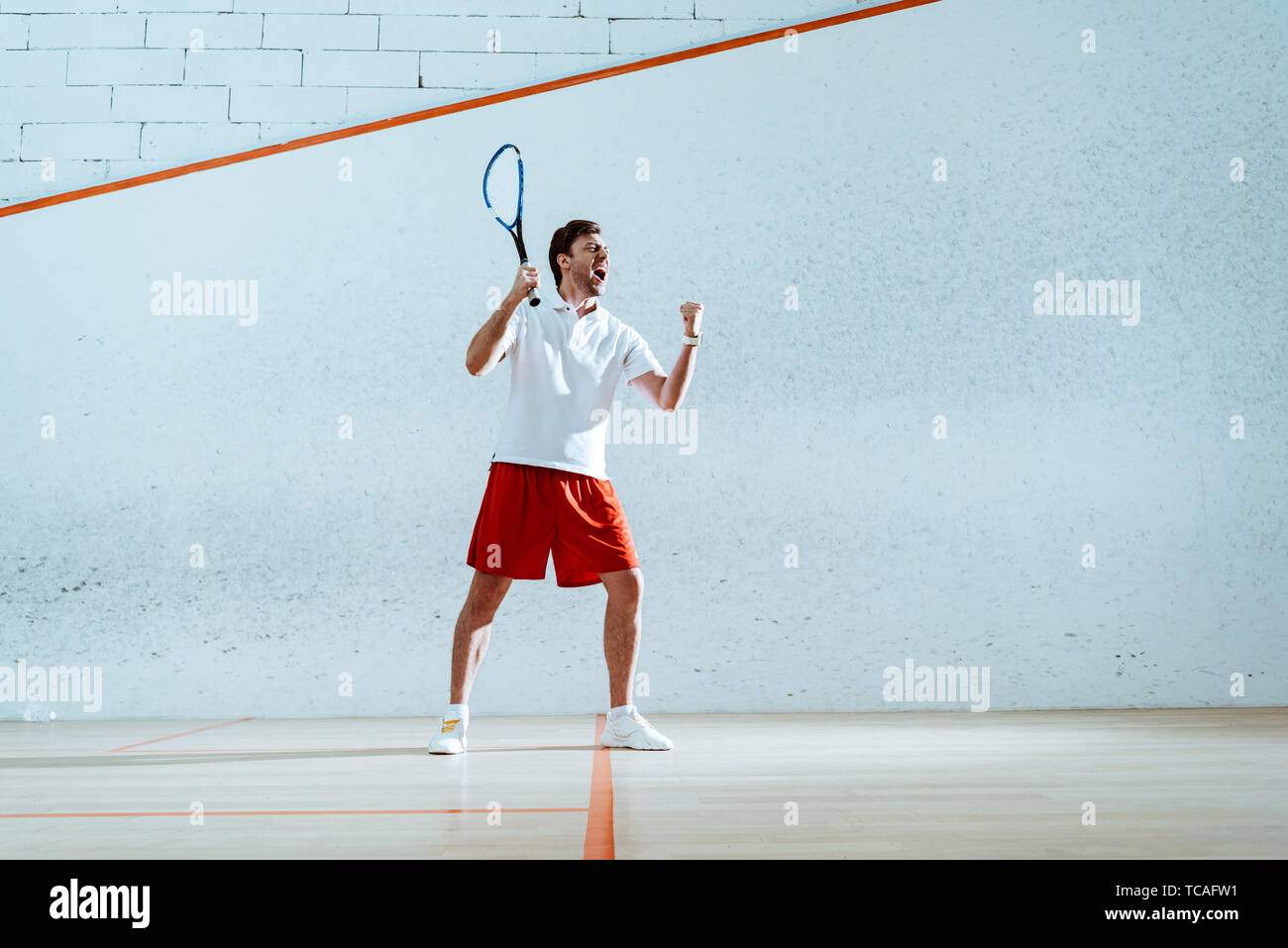 Full length view of happy squash player with racket showing yes gesture ...