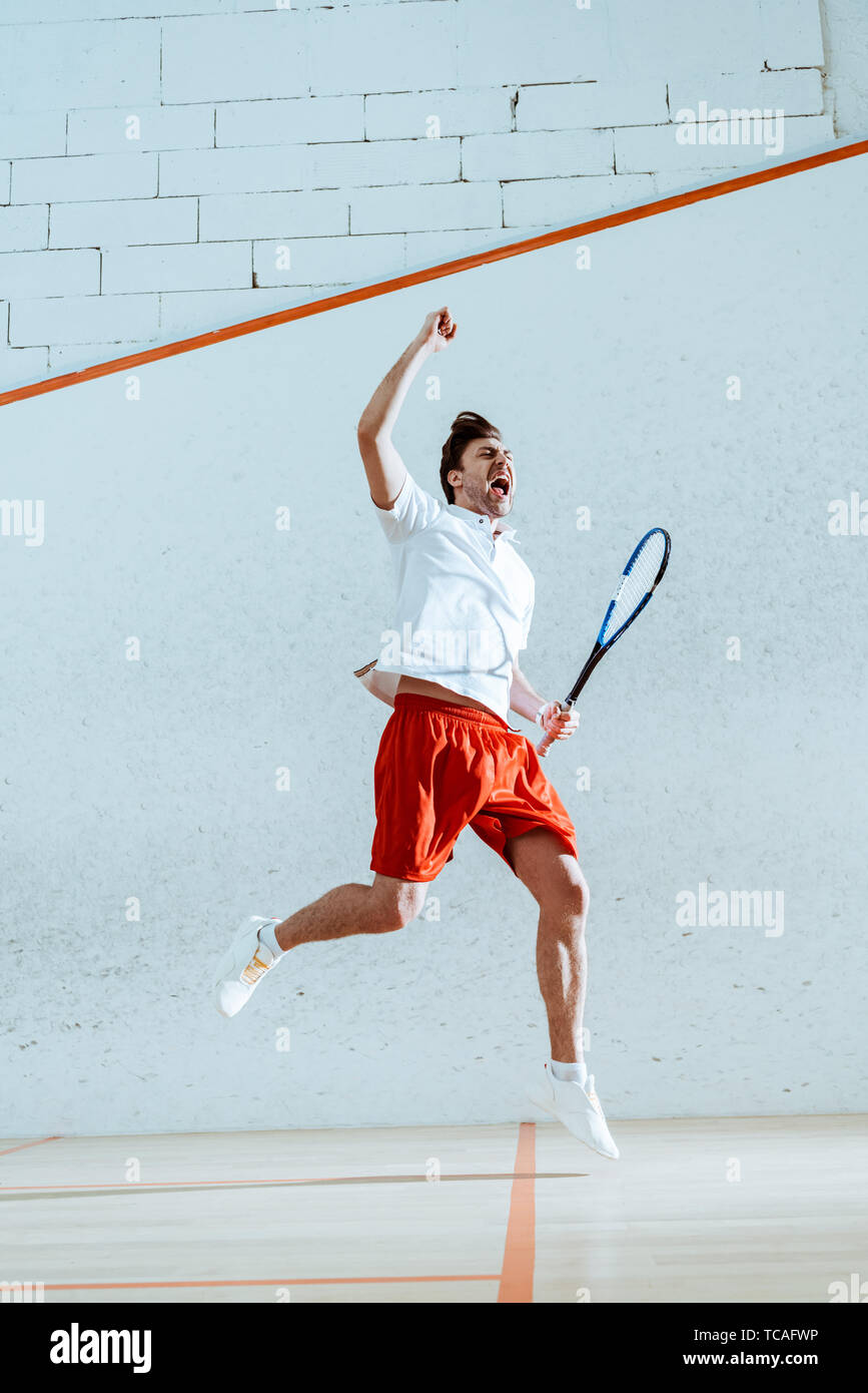 Full length view of happy squash player with racket showing yes gesture ...