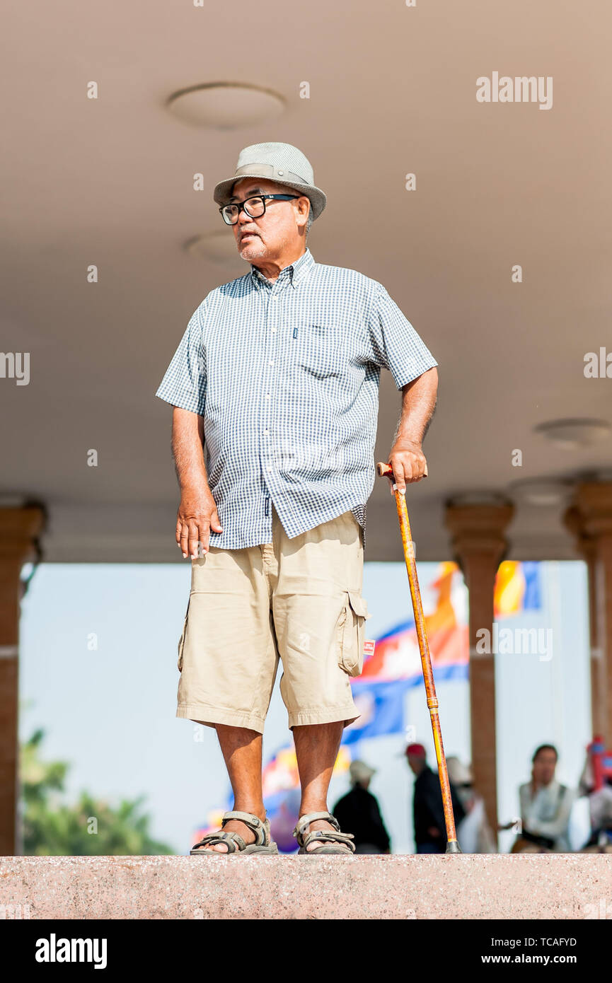 An elderly Cambodian man makes his way down the steps with a walking ...
