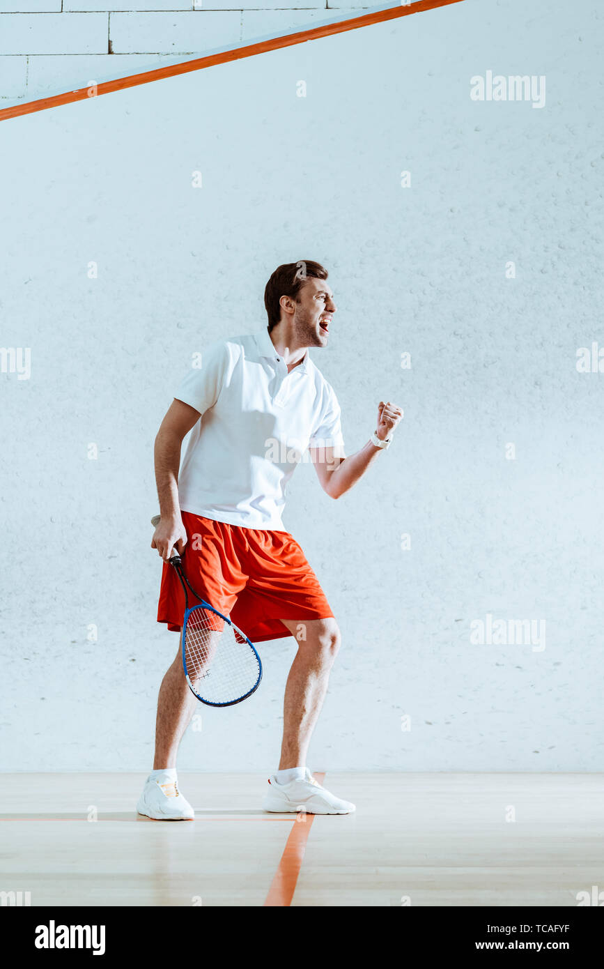 Full length view of happy squash player with racket showing yes gesture ...