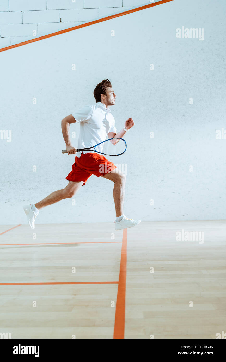 Full length view of sportsman with racket running while playing squash ...