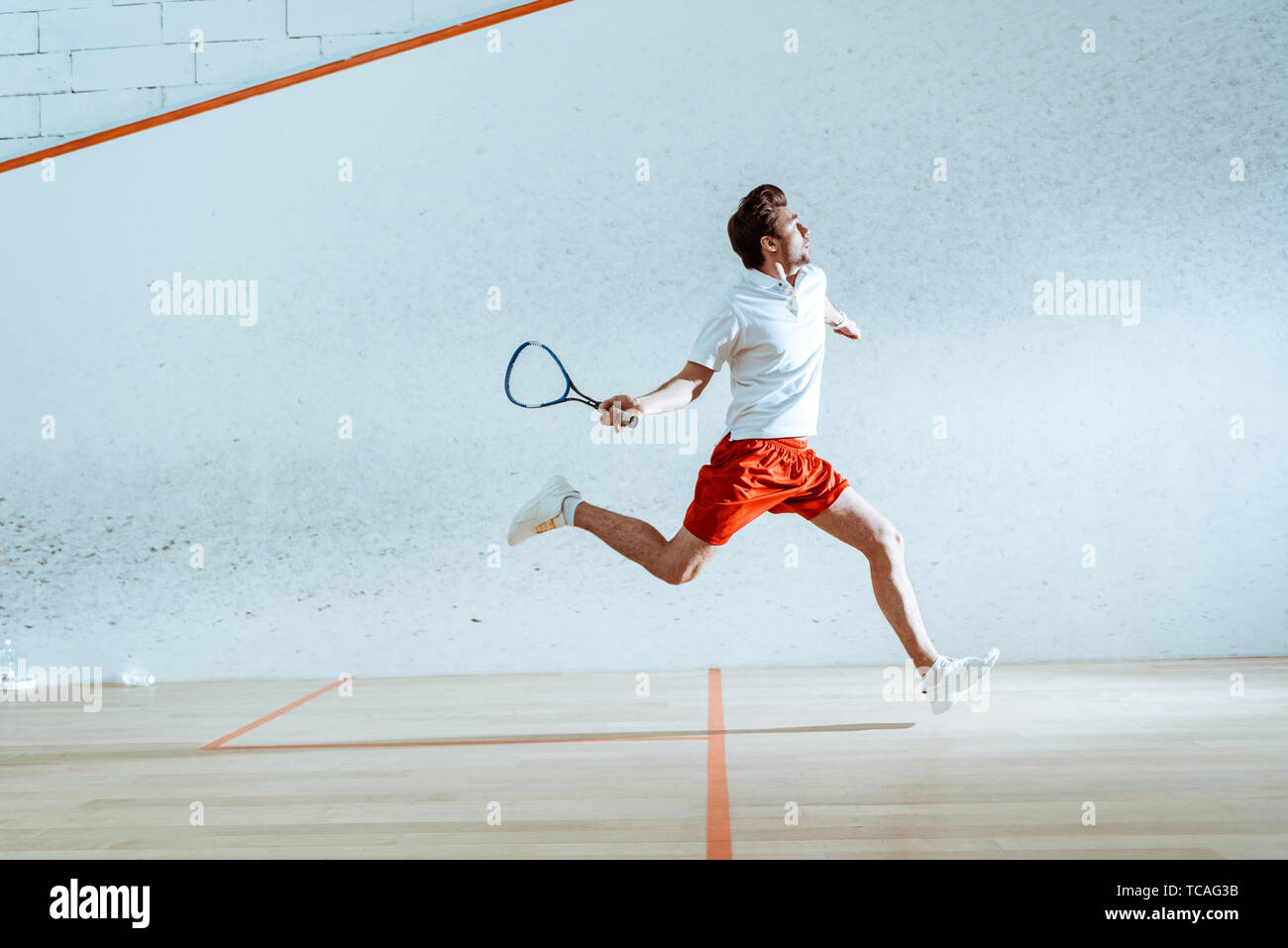 Full length view of sportsman with racket running while playing squash ...