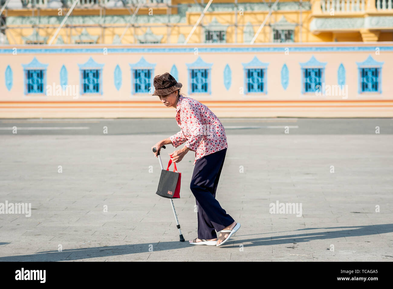 A very old Cambodian lady makes her way across the road in front of The ...
