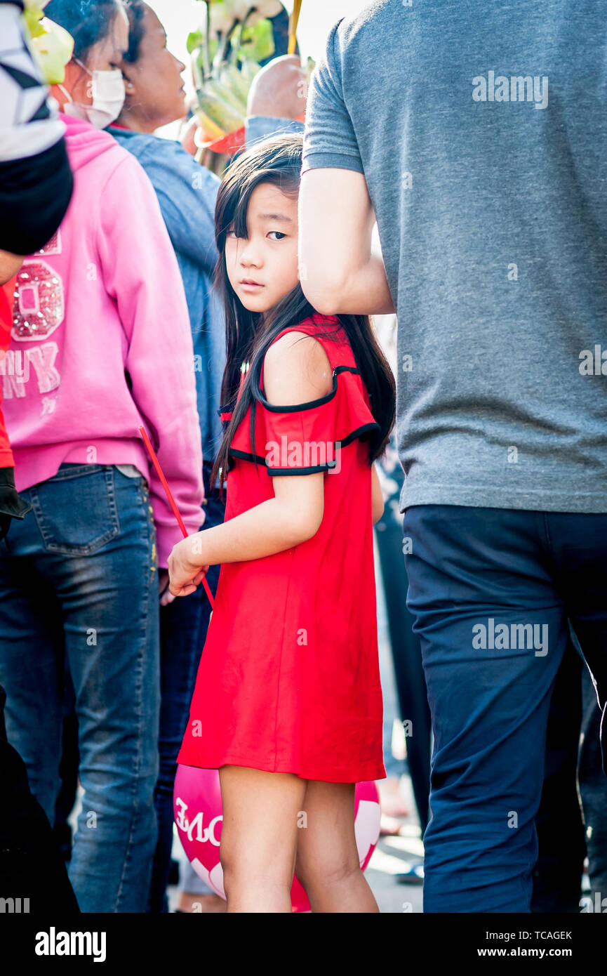 A Shy Little Cambodian Girl Holding A Balloon Waits Outside A Temple As Incense Smoke Wafts