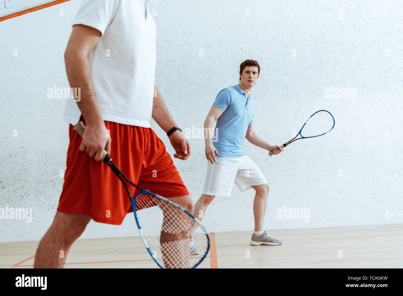 Cropped view of squash players with rackets in four-walled court Stock ...