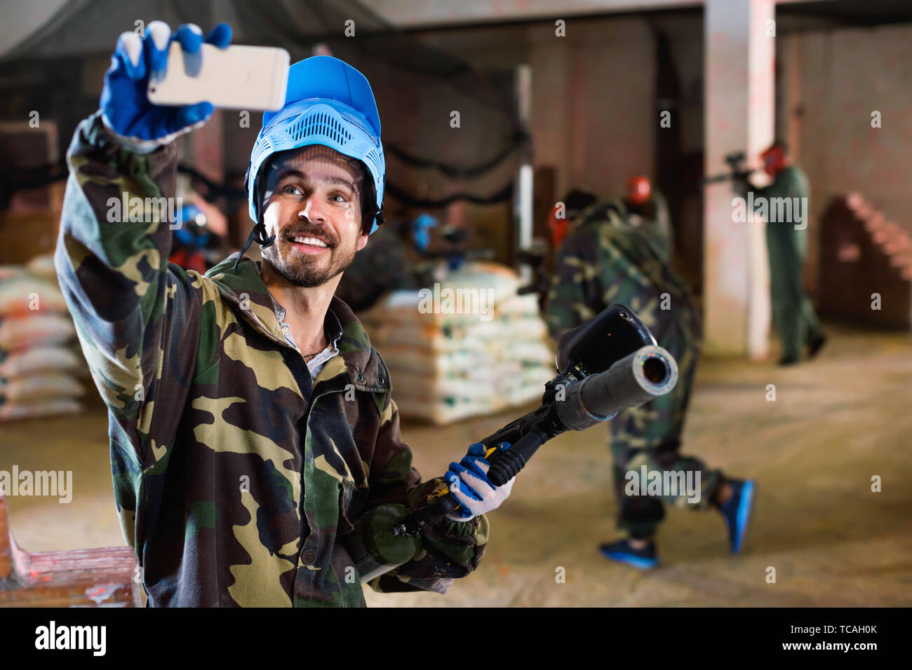 Young cheerful man in blue mask is making selfie on battlefield of ...