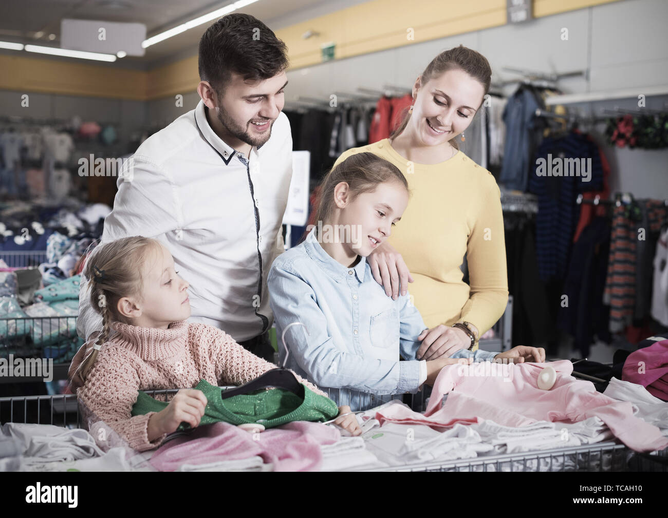 young family with two little girls choosing new clothes in mall Stock ...