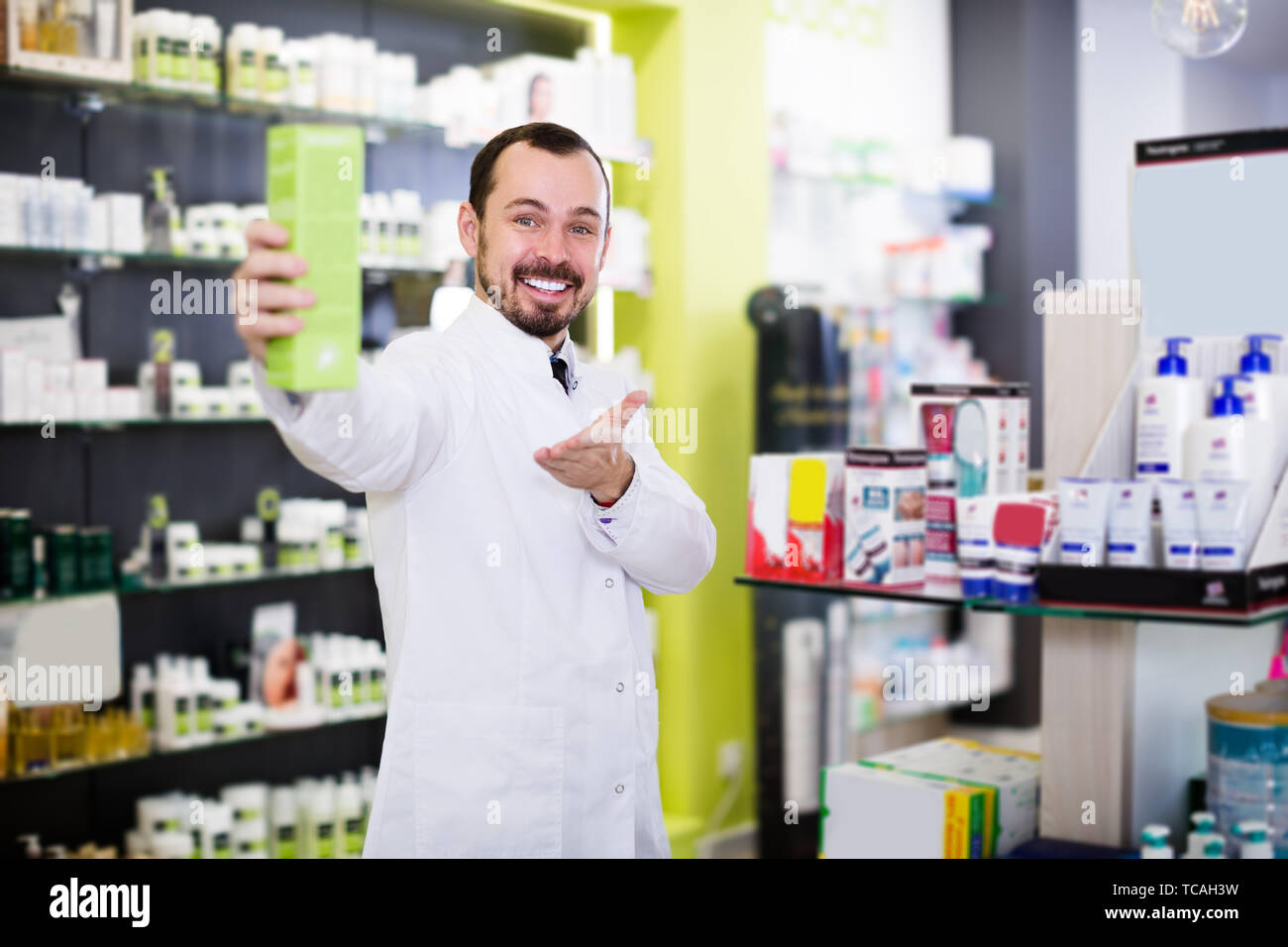 Positive man pharmacist showing right drug in pharmacy Stock Photo - Alamy