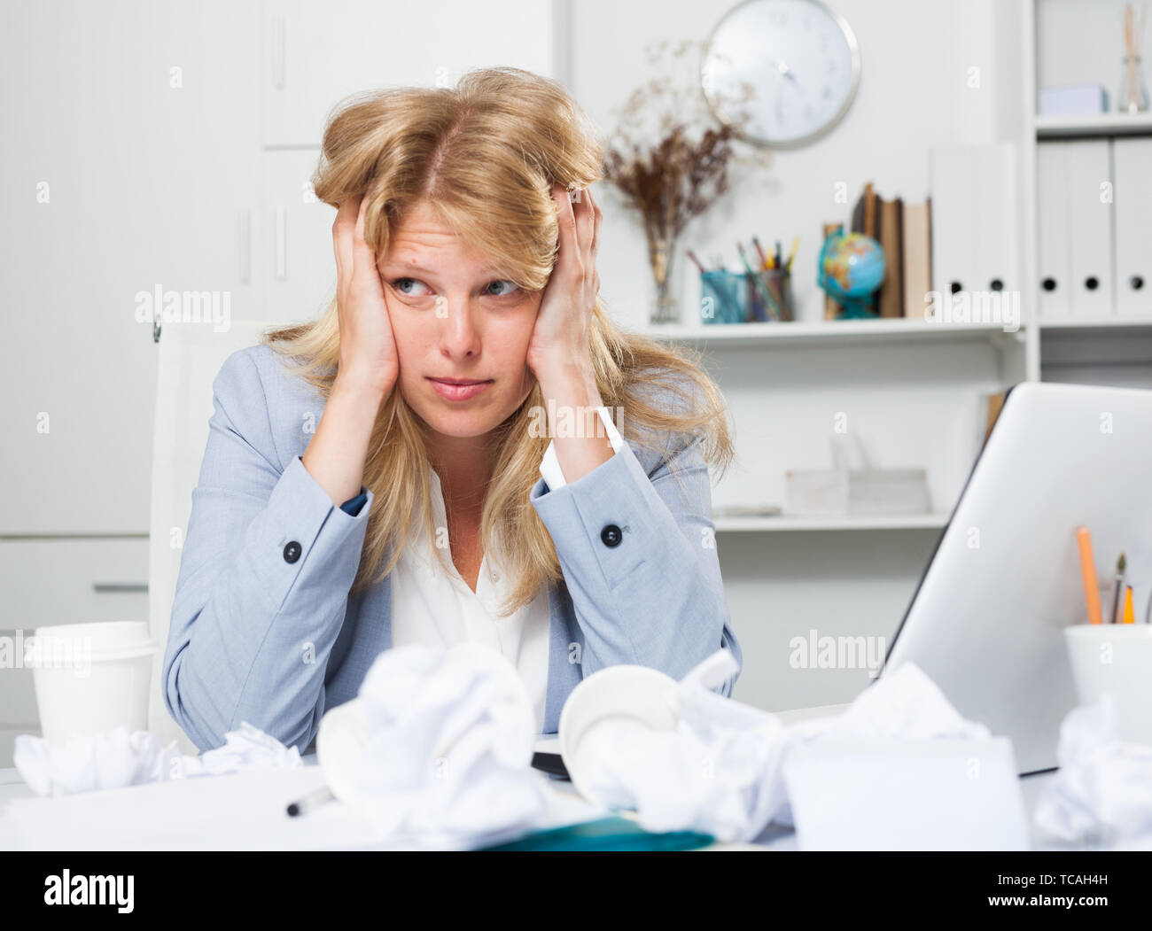 Frustrated business woman sitting among papers and feeling tired after ...