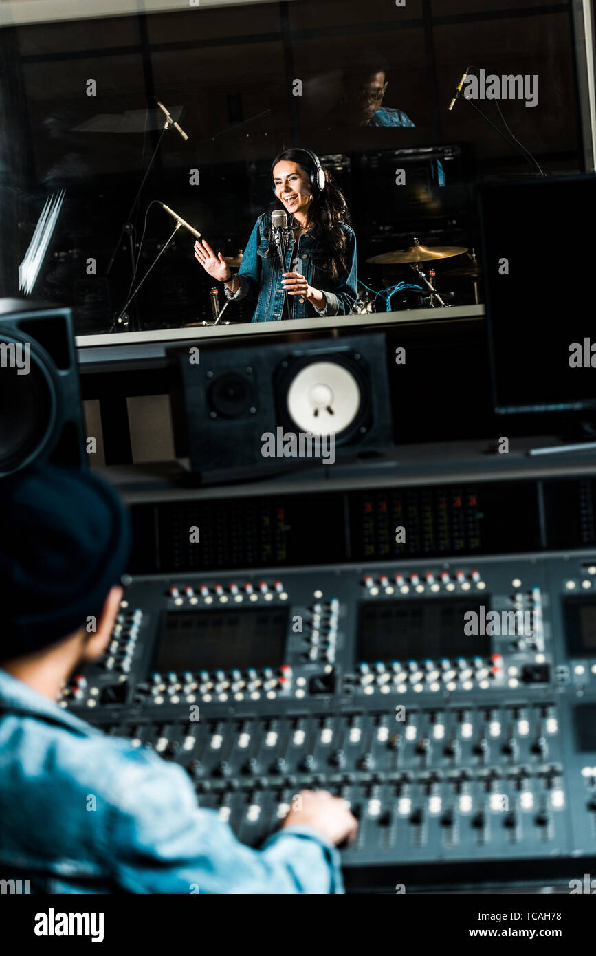 selective focus of mixed race sound producer working at mixing console ...
