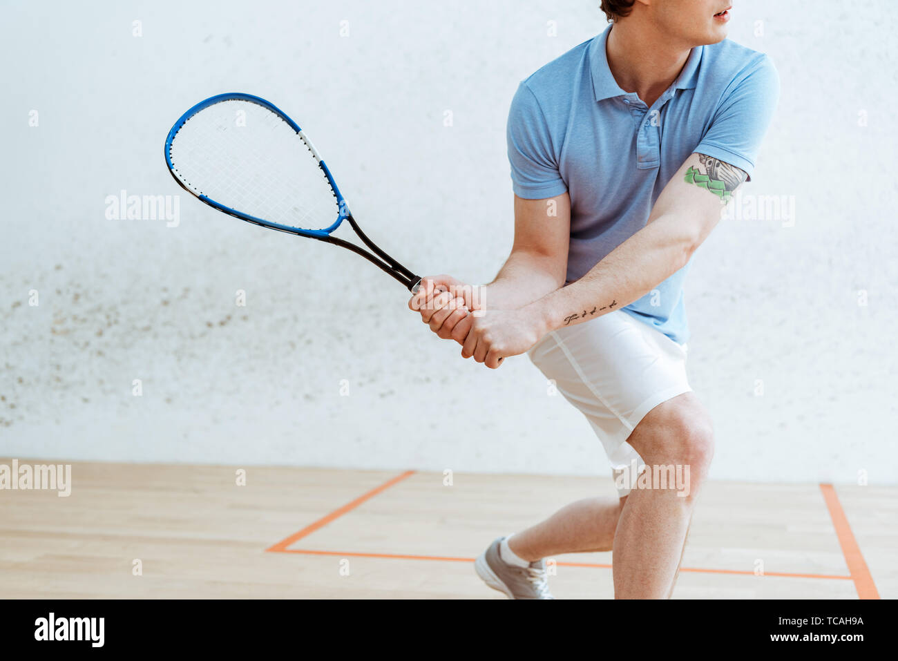 Cropped view of sportsman in blue polo shirt playing squash in sports ...