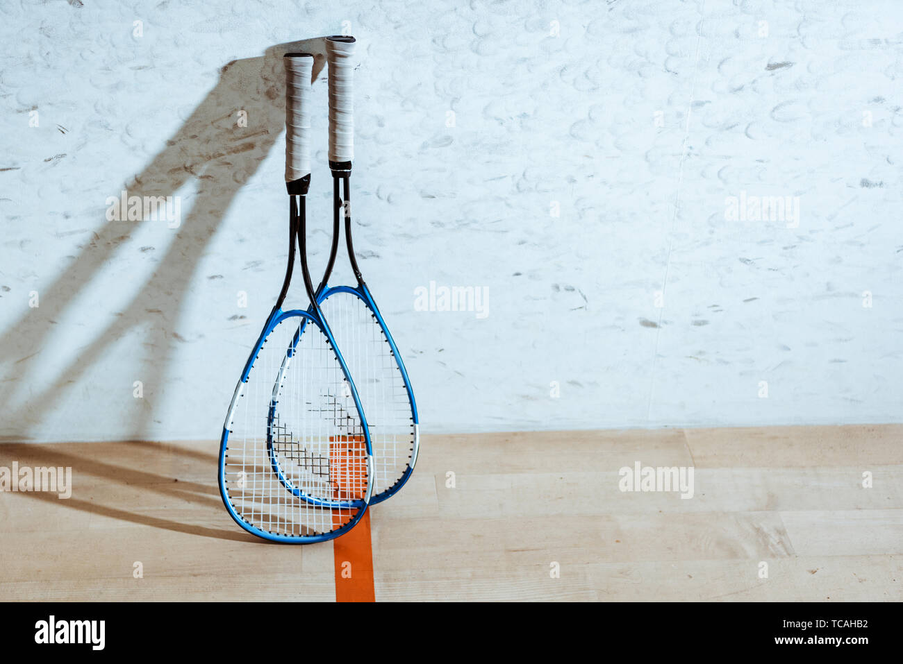 Two squash rackets on wooden floor in four-walled court Stock Photo - Alamy