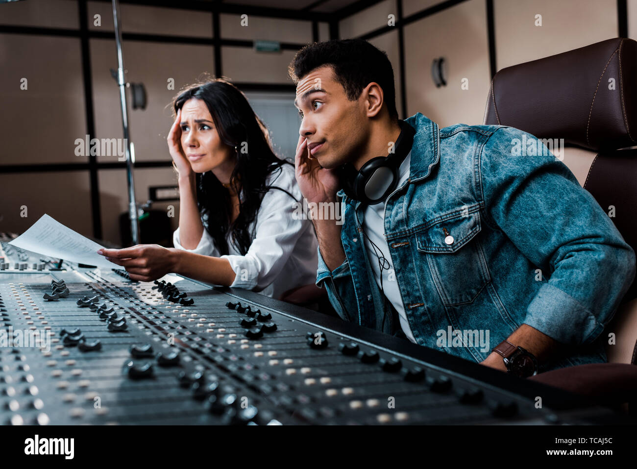 two thoughtful sound producers working at mixing console in recording ...
