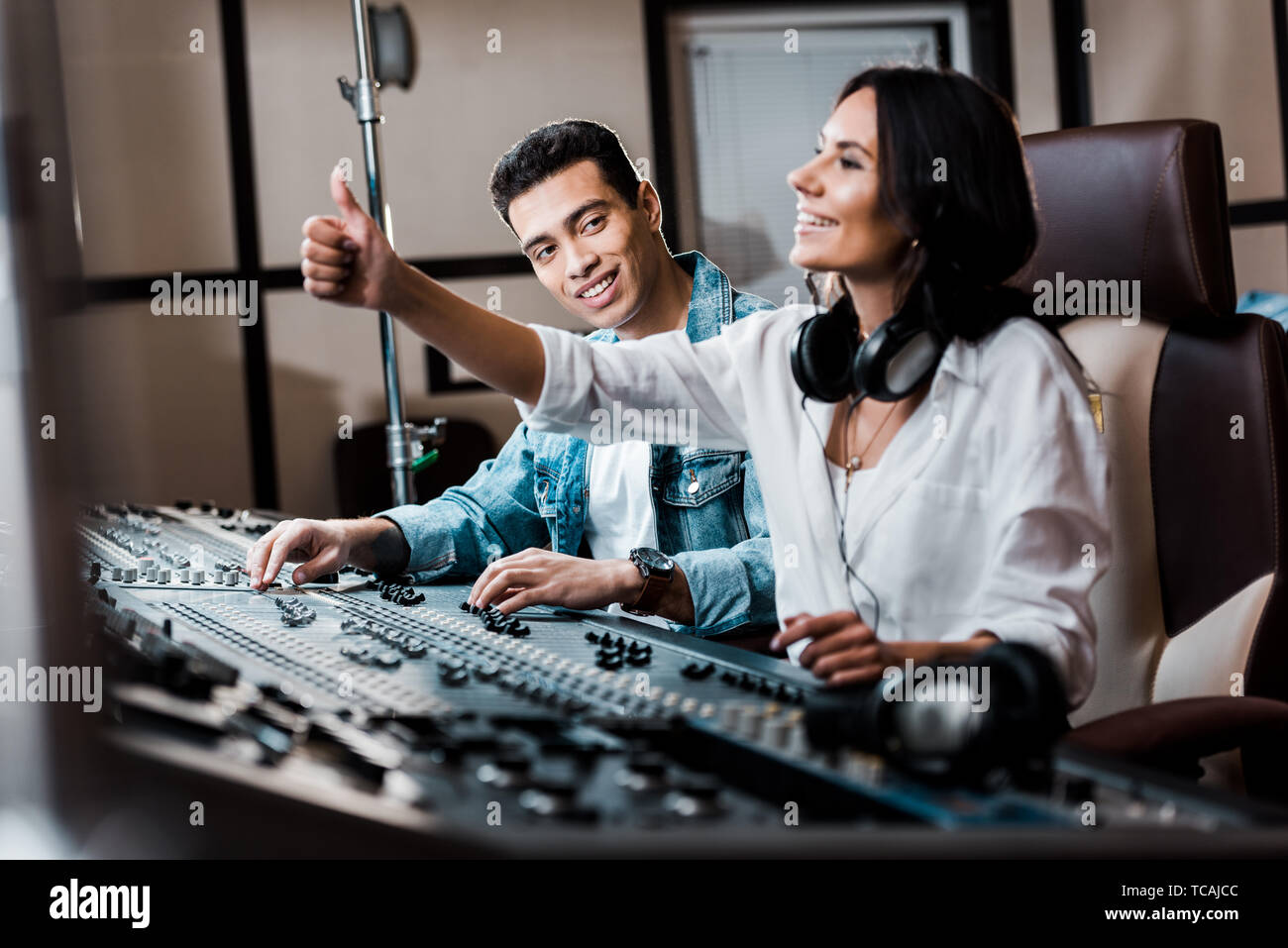 selective focus of cheerful sound produce showing thumb up while ...