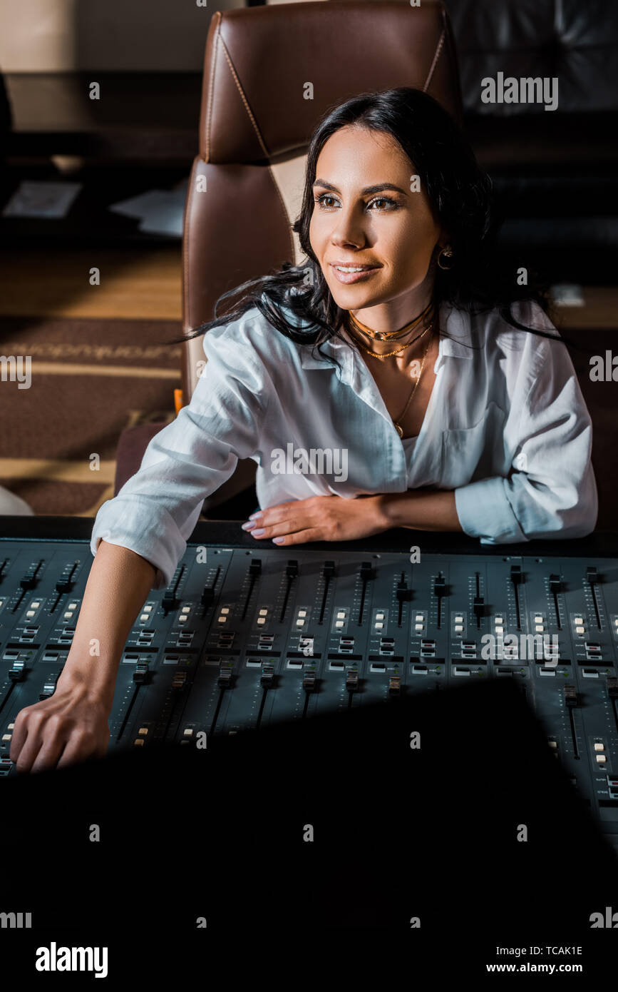 beautiful smiling sound producer working at mixing console in recording ...