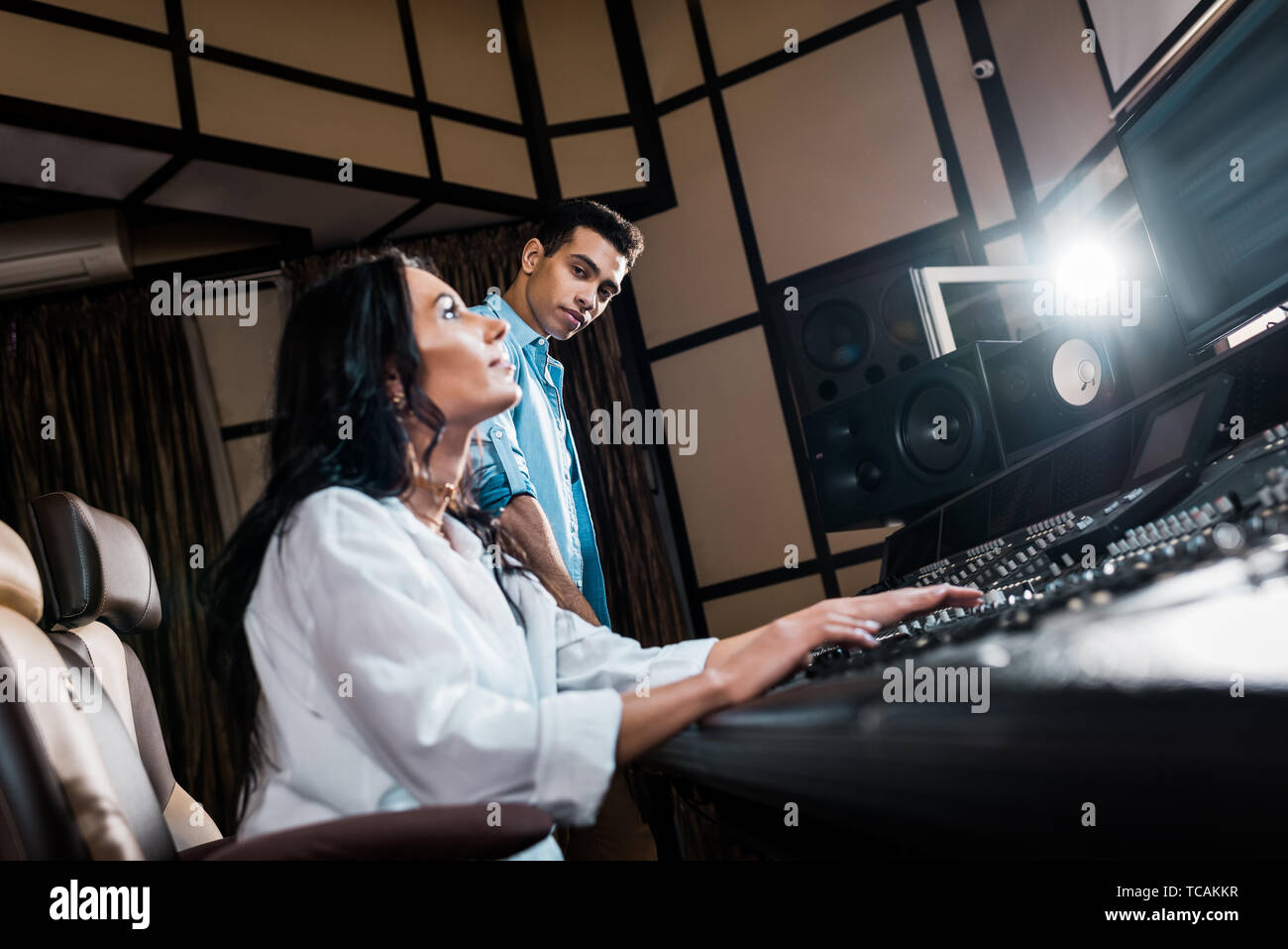 young multicultural sound producers working at sound console in ...