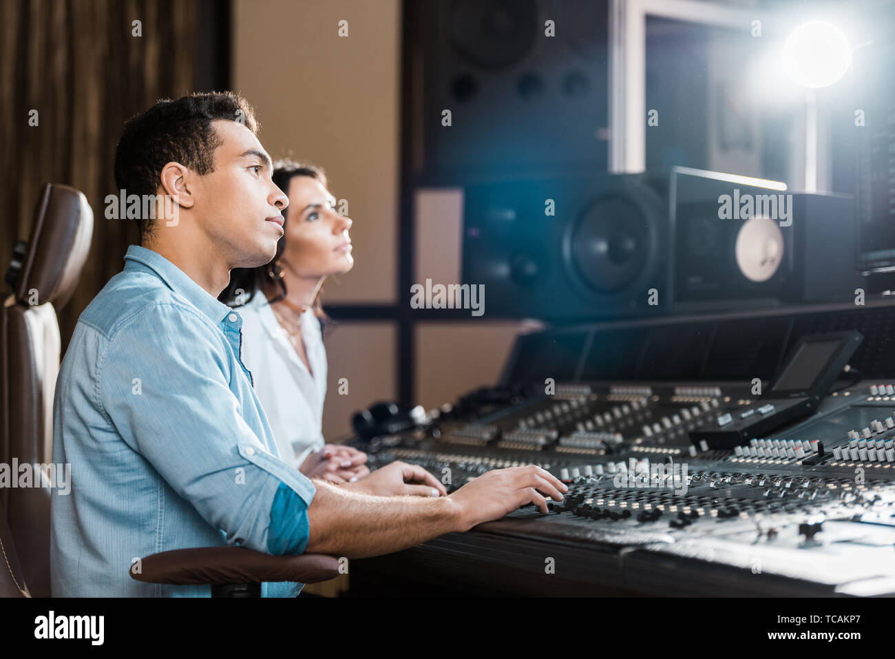 two multicultural musicians working at mixing console in recording ...