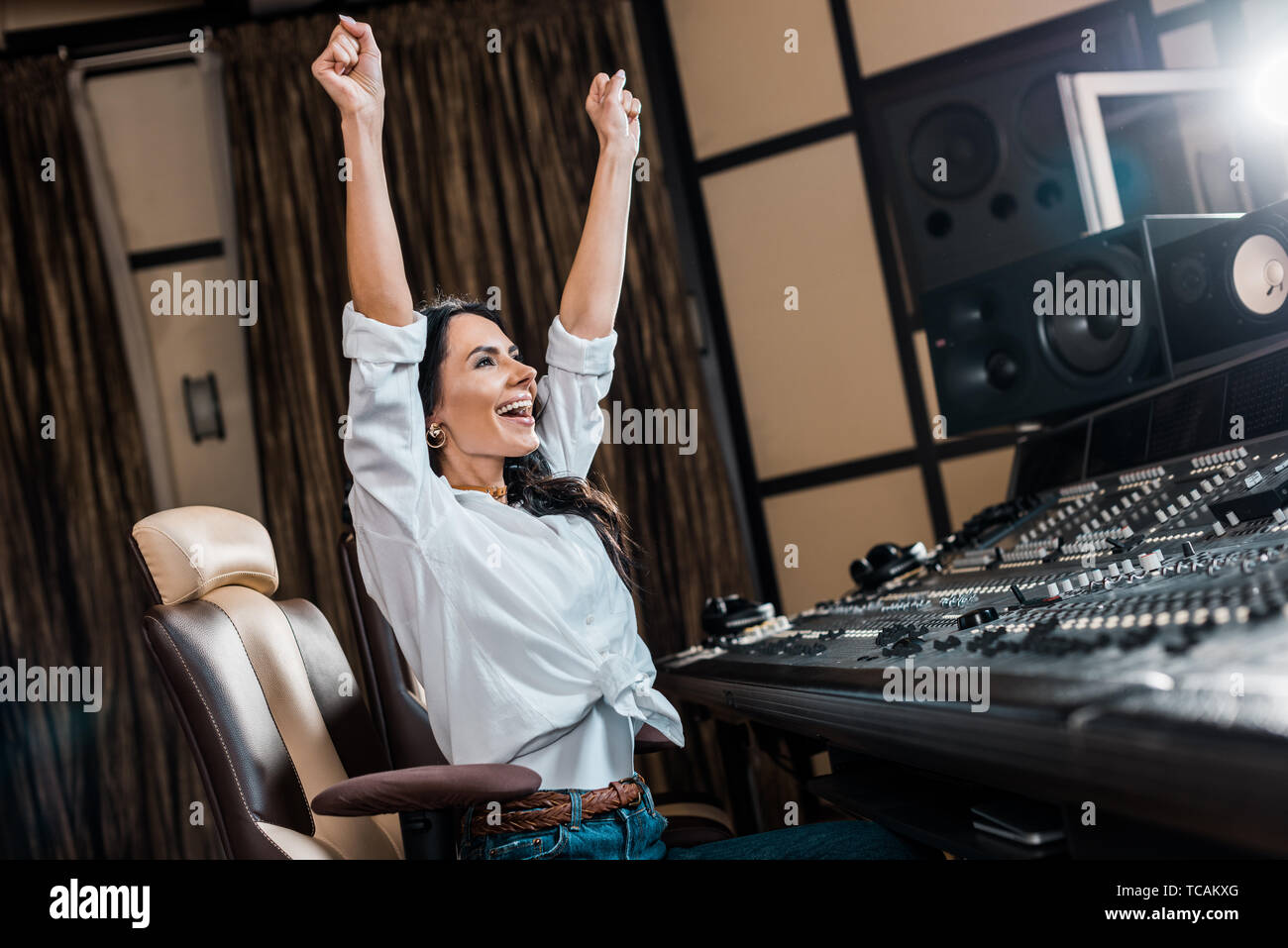 happy sound producer showing success gesture near mixing console in ...