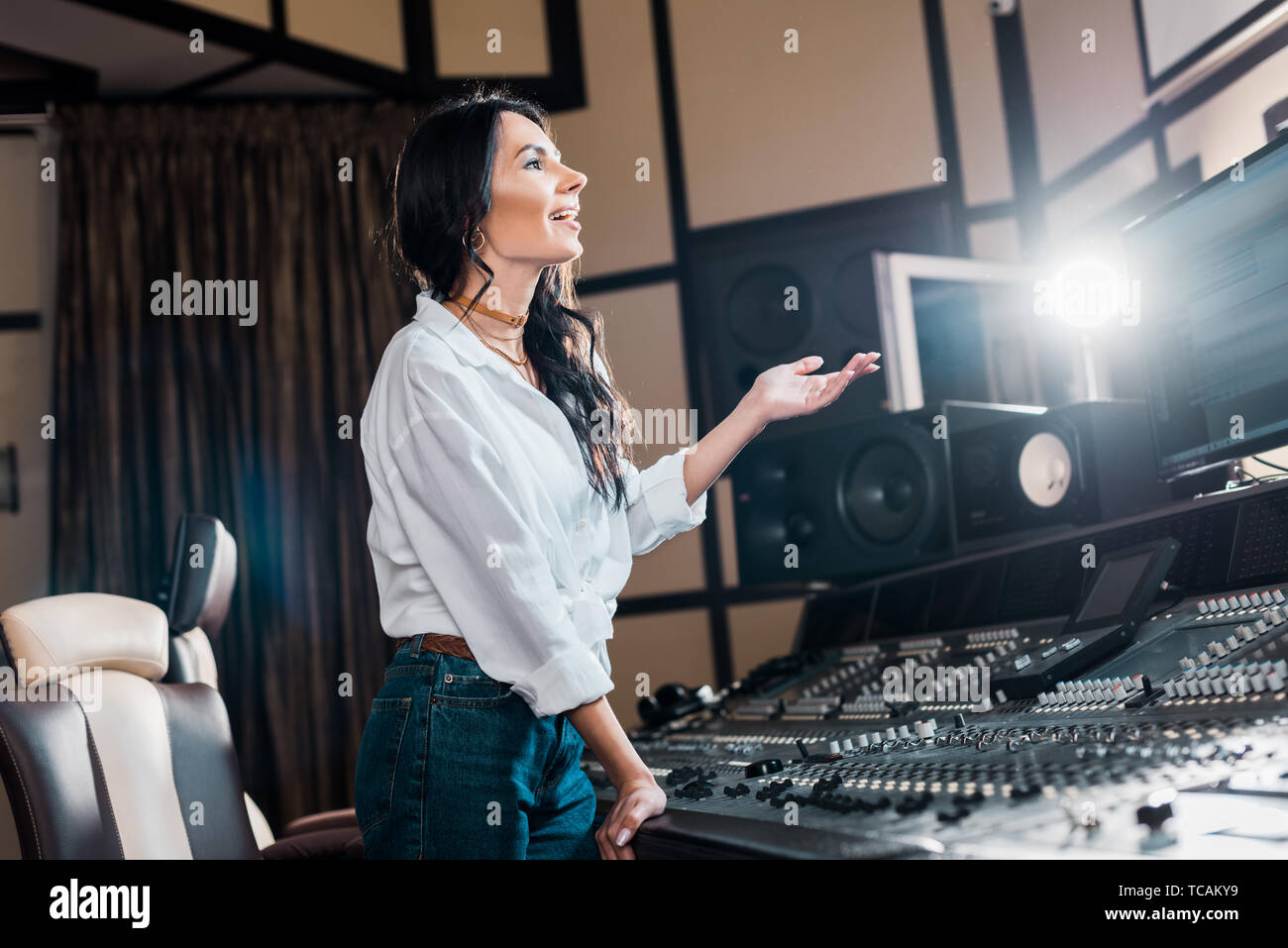 happy sound producer applauding in recording studio near mixing console ...