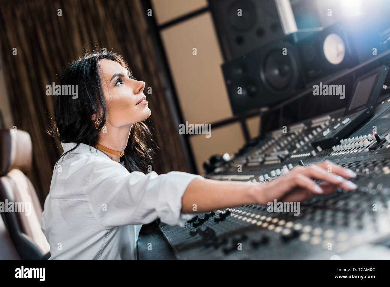 pretty smiling musician working in recording studio at mixing console ...