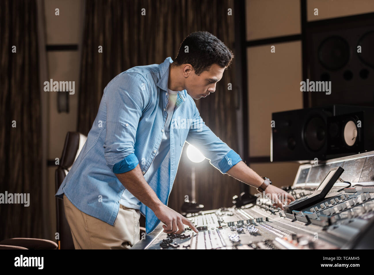 concentrated sound producer working at mixing console in recording ...