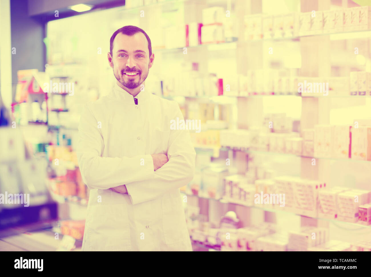 Smiling happy positive male pharmacist demonstrating assortment of ...