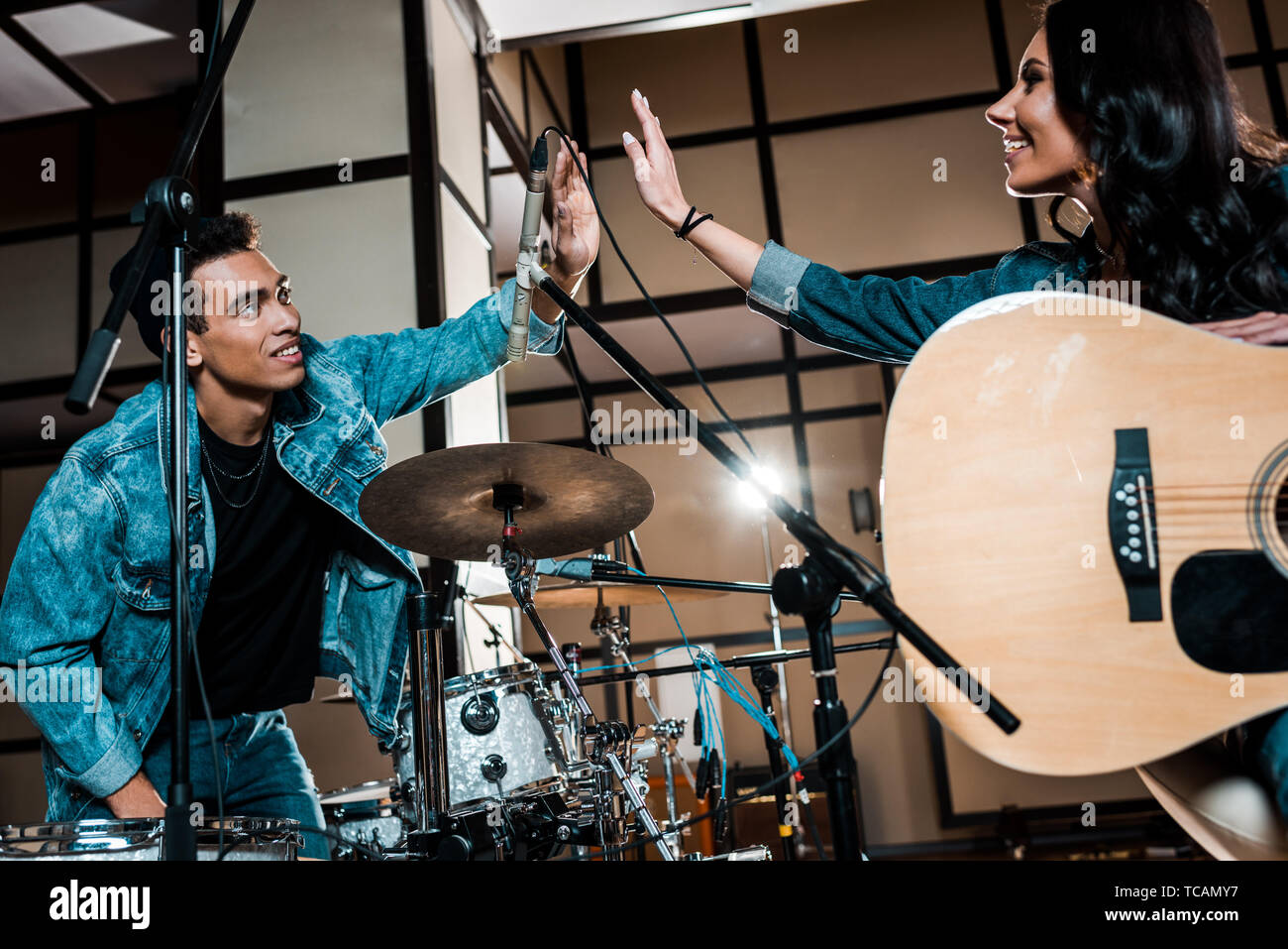 young smiling multicultural musicians giving high five in recording ...
