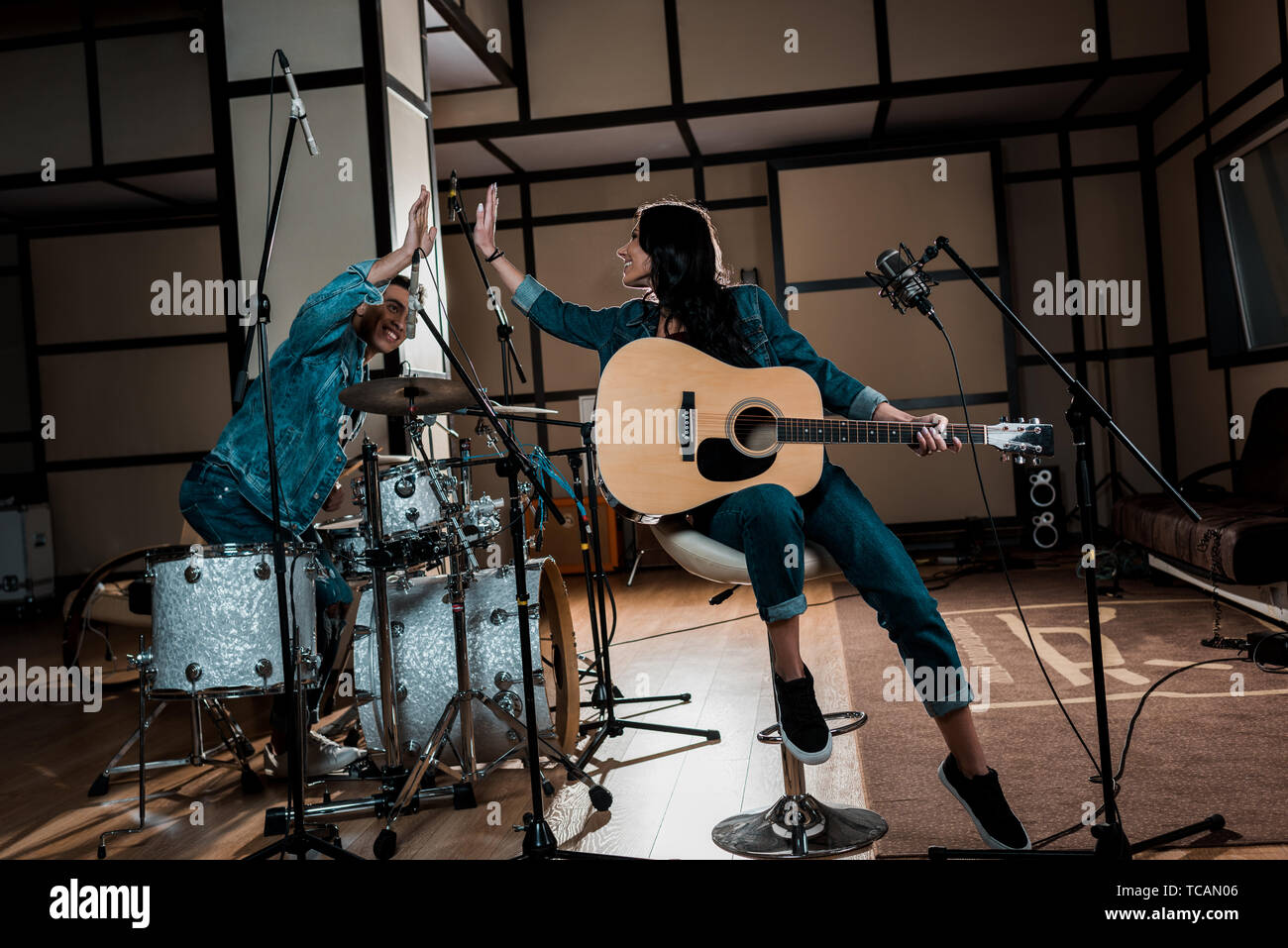 young inspired multicultural musicians giving high five in recording ...