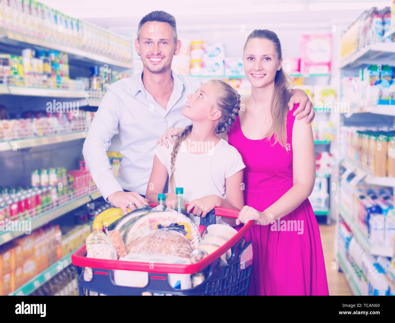 Portrait of customers which is standing with full trolley of goods in ...