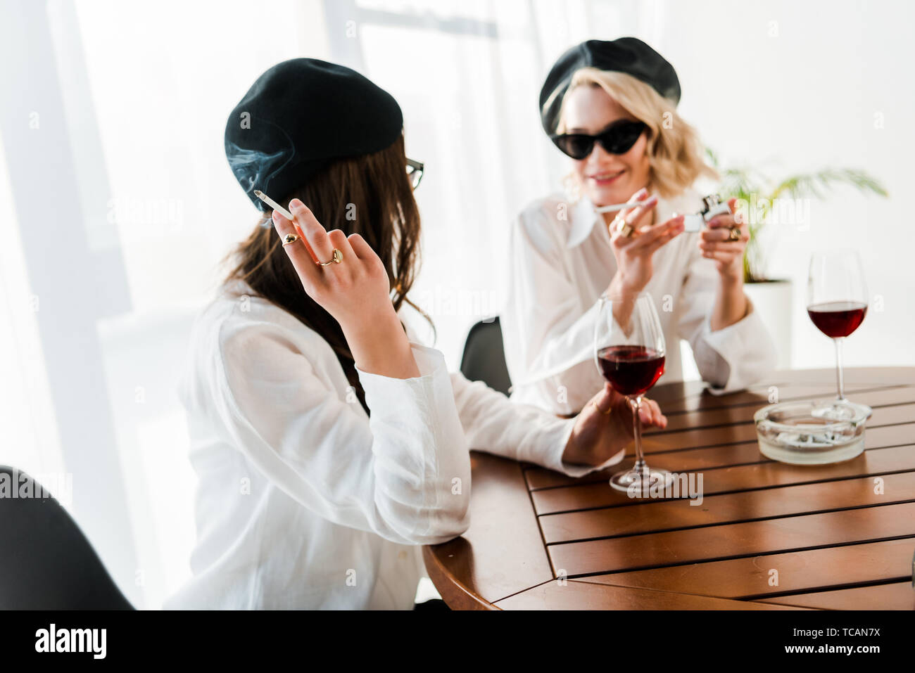 brunette and blonde women in black berets and sunglasses drinking red ...