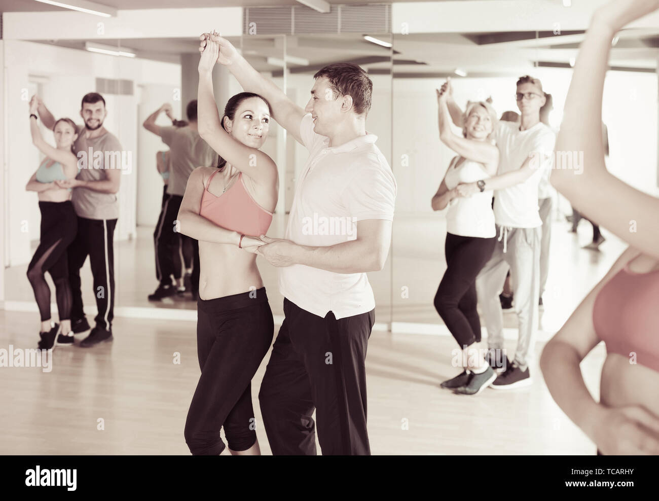 happy spanish men and women of different ages dancing salsa in dance ...