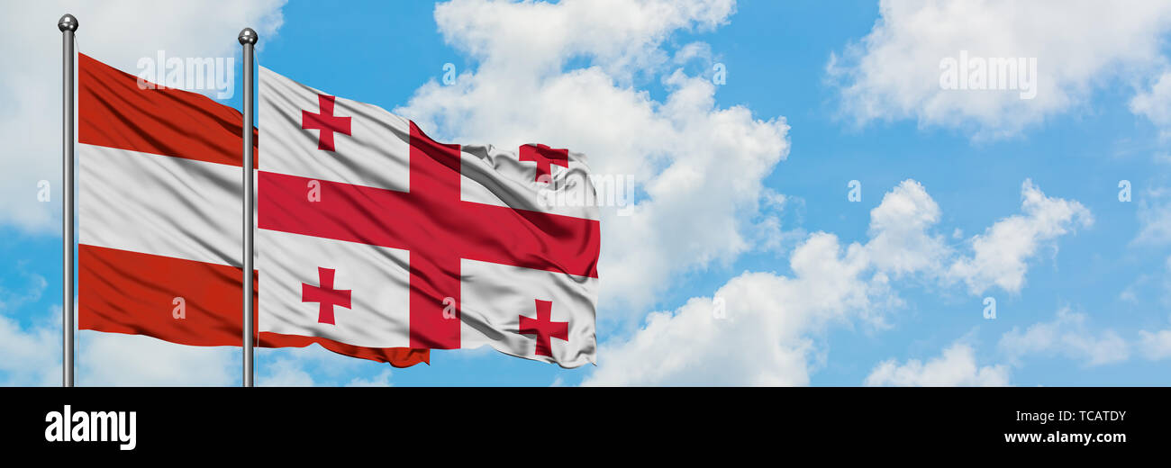 Austria and Georgia flag waving in the wind against white cloudy blue ...