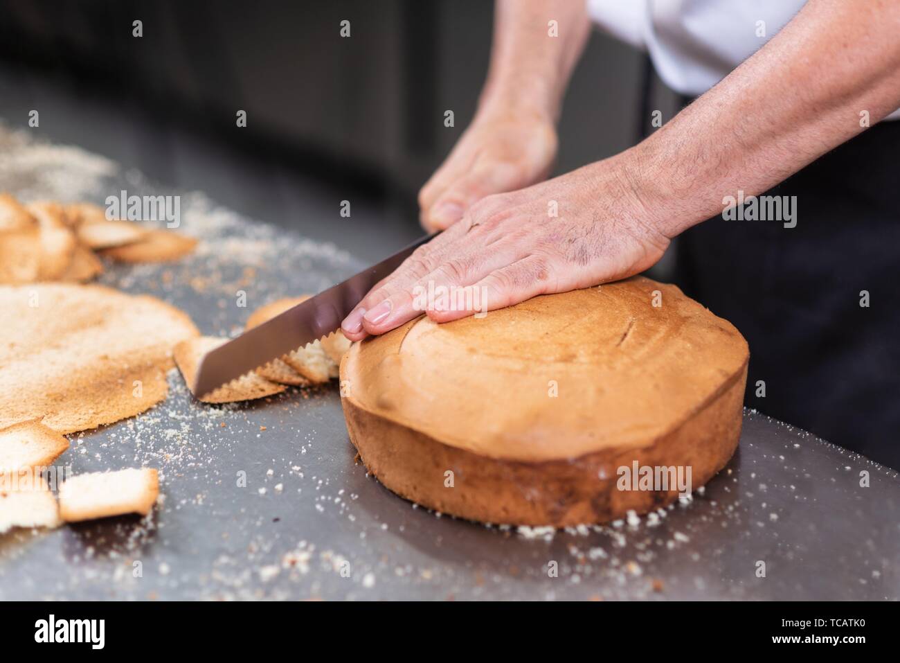 pastry chef cutting the sponge cake on layers. Cake production process ...