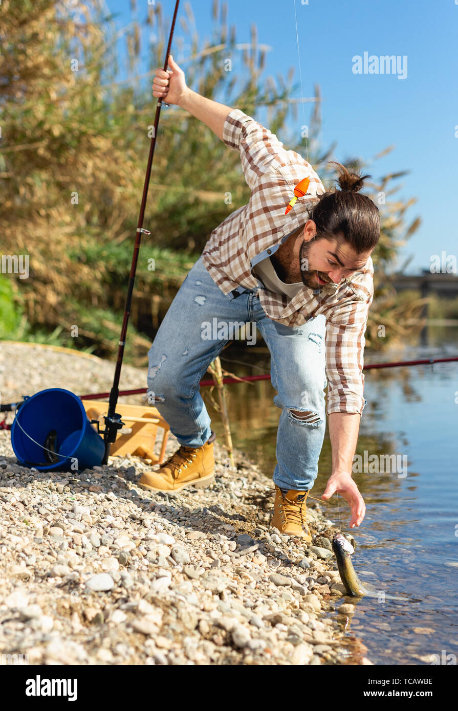 Happy fisherman pulls fish out of the river Stock Photo - Alamy