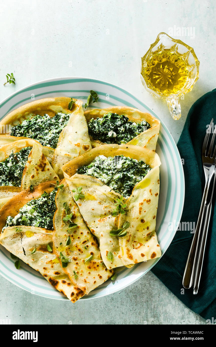 Traditional Italian pancakes crepes with spinach and ricotta on a ...