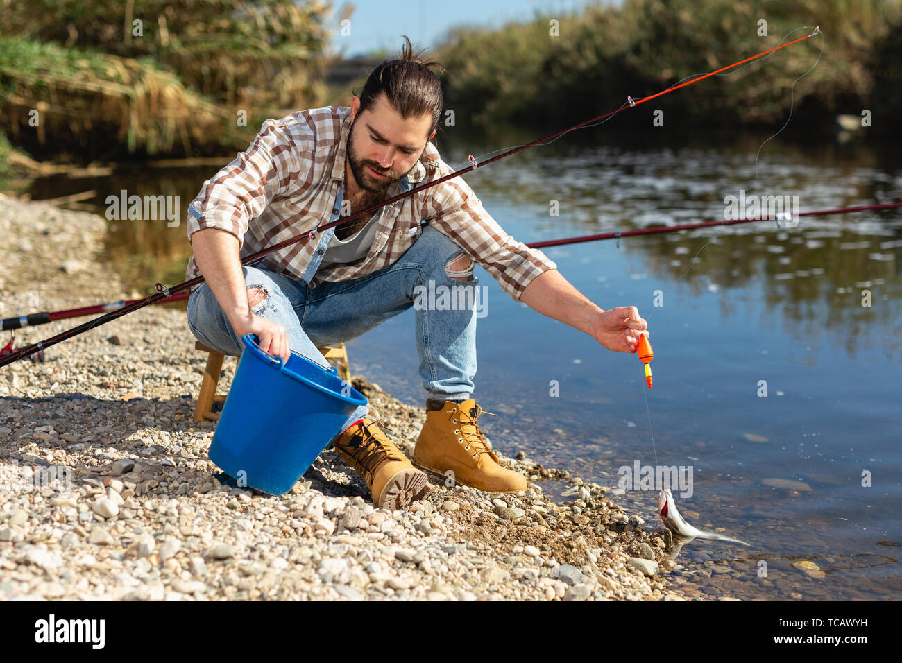 Positive fisherman holding catch freshwater fish in hands Stock Photo ...