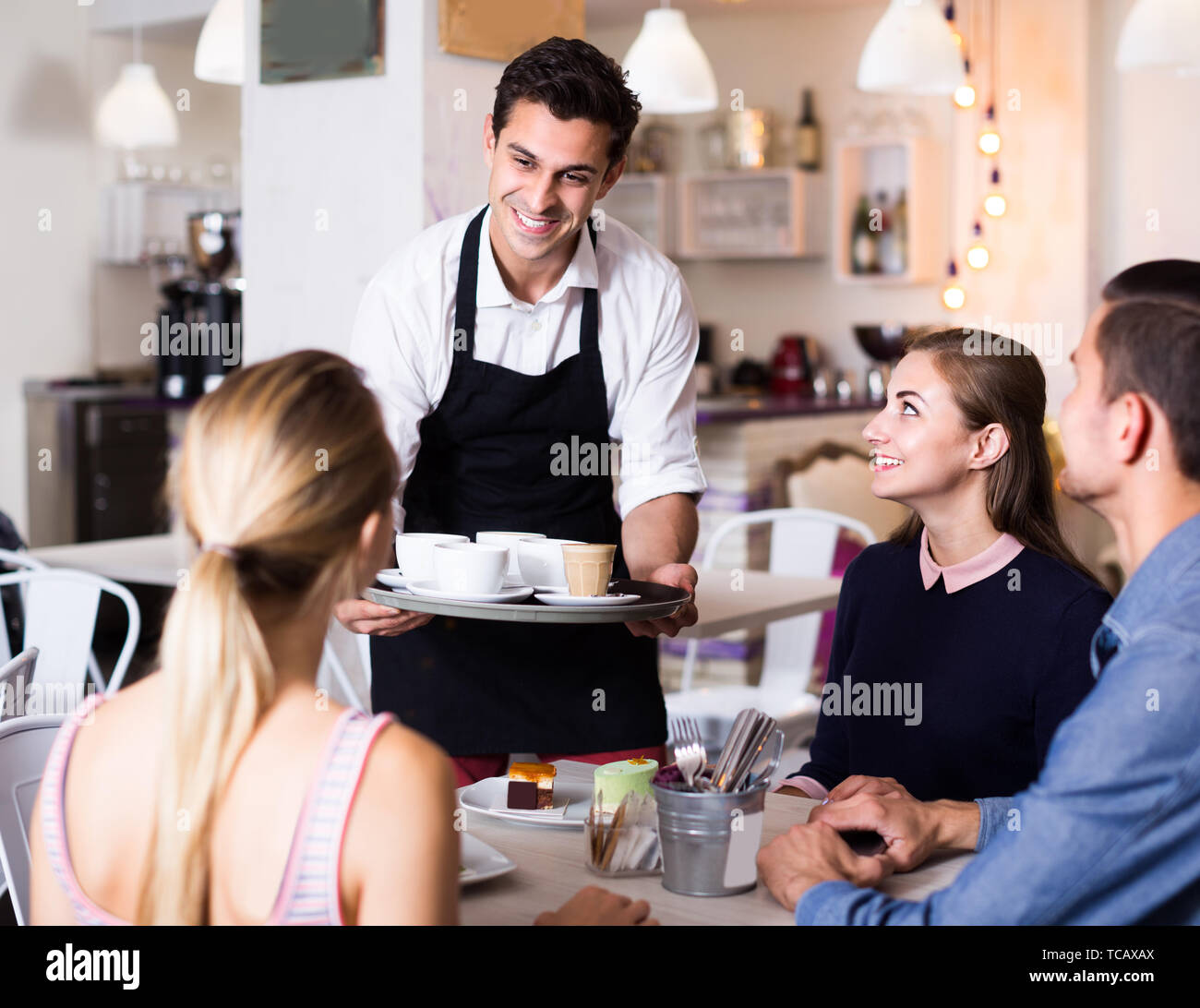 Male is bringing drinking and delicious desserts to visitors of cafe ...