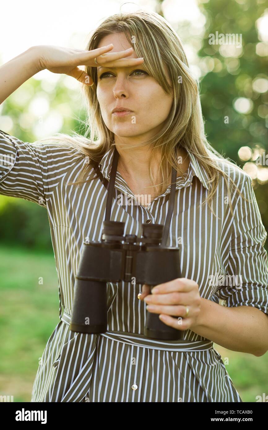 A woman look into distance covering eyes, holding binoculars in the ...