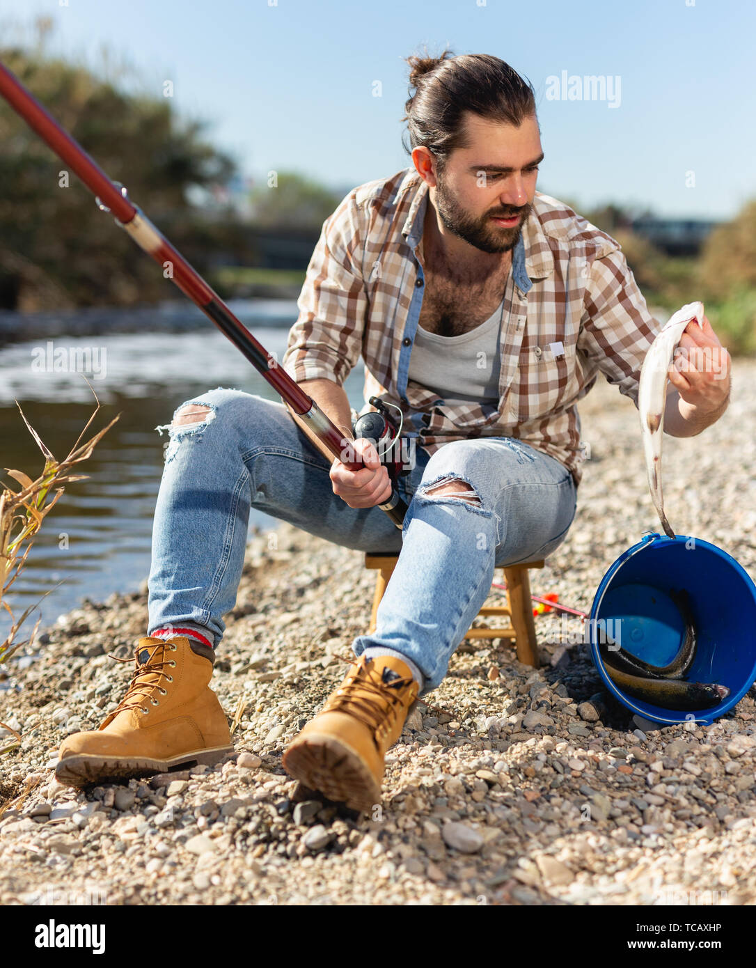 Bearded adult man posing with fish near river in summertime Stock Photo ...