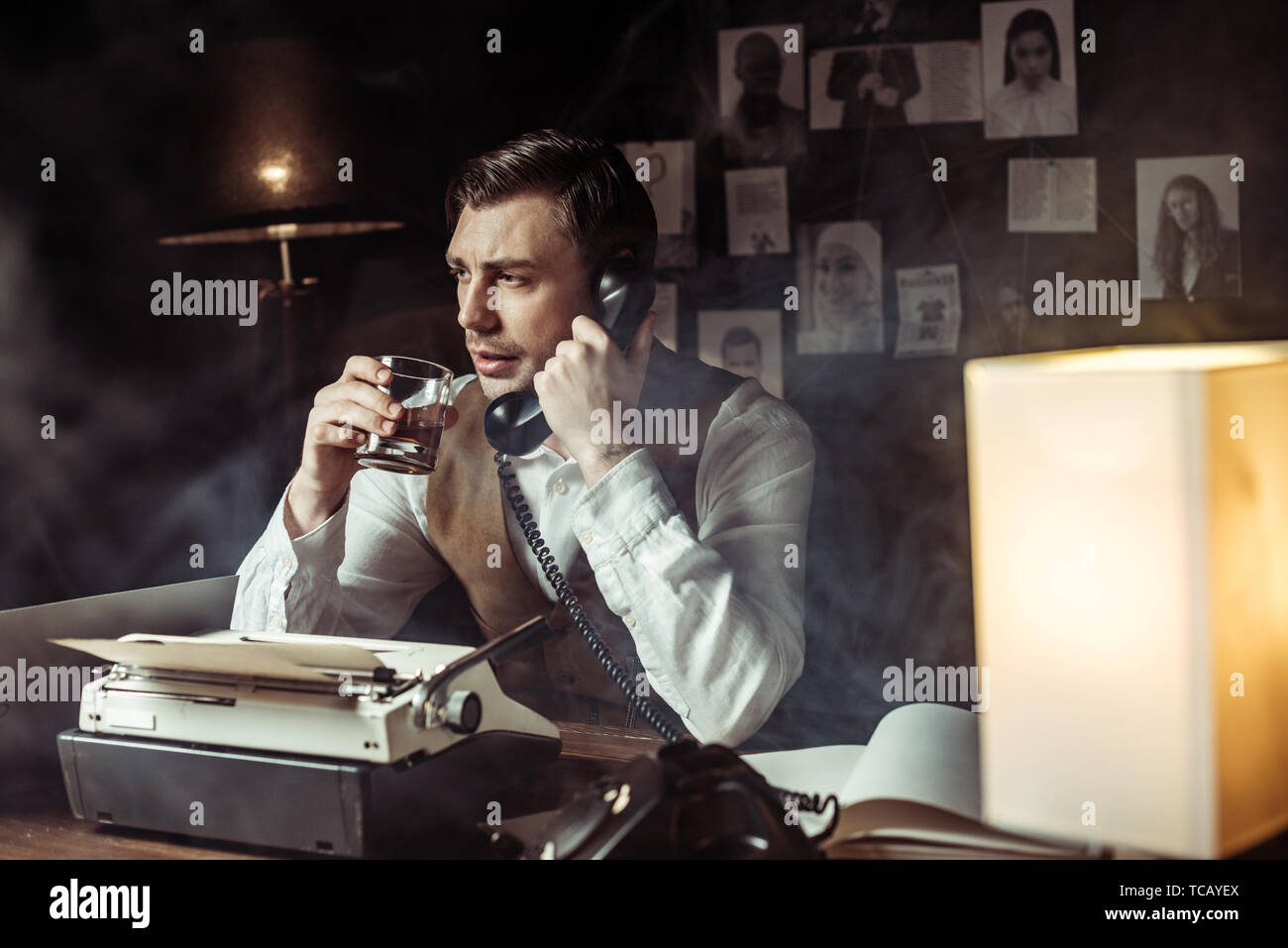 Detective talking on telephone and drinking cognac in office Stock ...