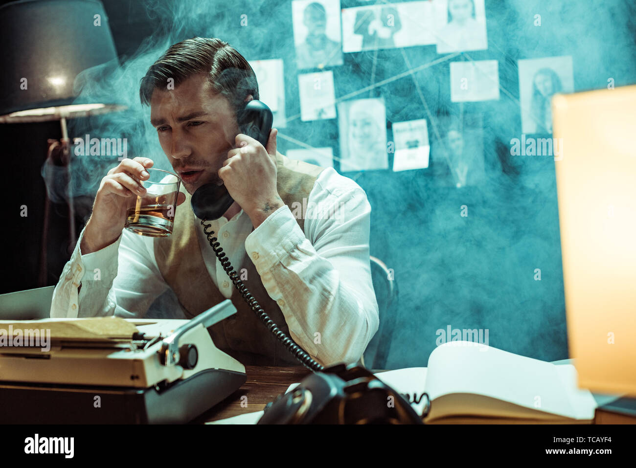 Detective talking on telephone and drinking cognac in office Stock ...